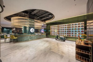 Uma área de recepção moderna com um balcão curvo, uma parede de discos de vinil e uma scooter.