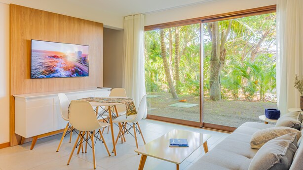 Uma sala de estar moderna com uma televisão grande, área de jantar e um sofá.