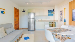Cozinha moderna com geladeira, mesa de jantar com cadeiras e um sofá em uma sala de estar.