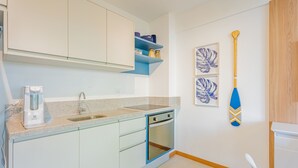 Uma cozinha moderna com armários em tons claros, lava-louças embutida e bancada com cafeteira.