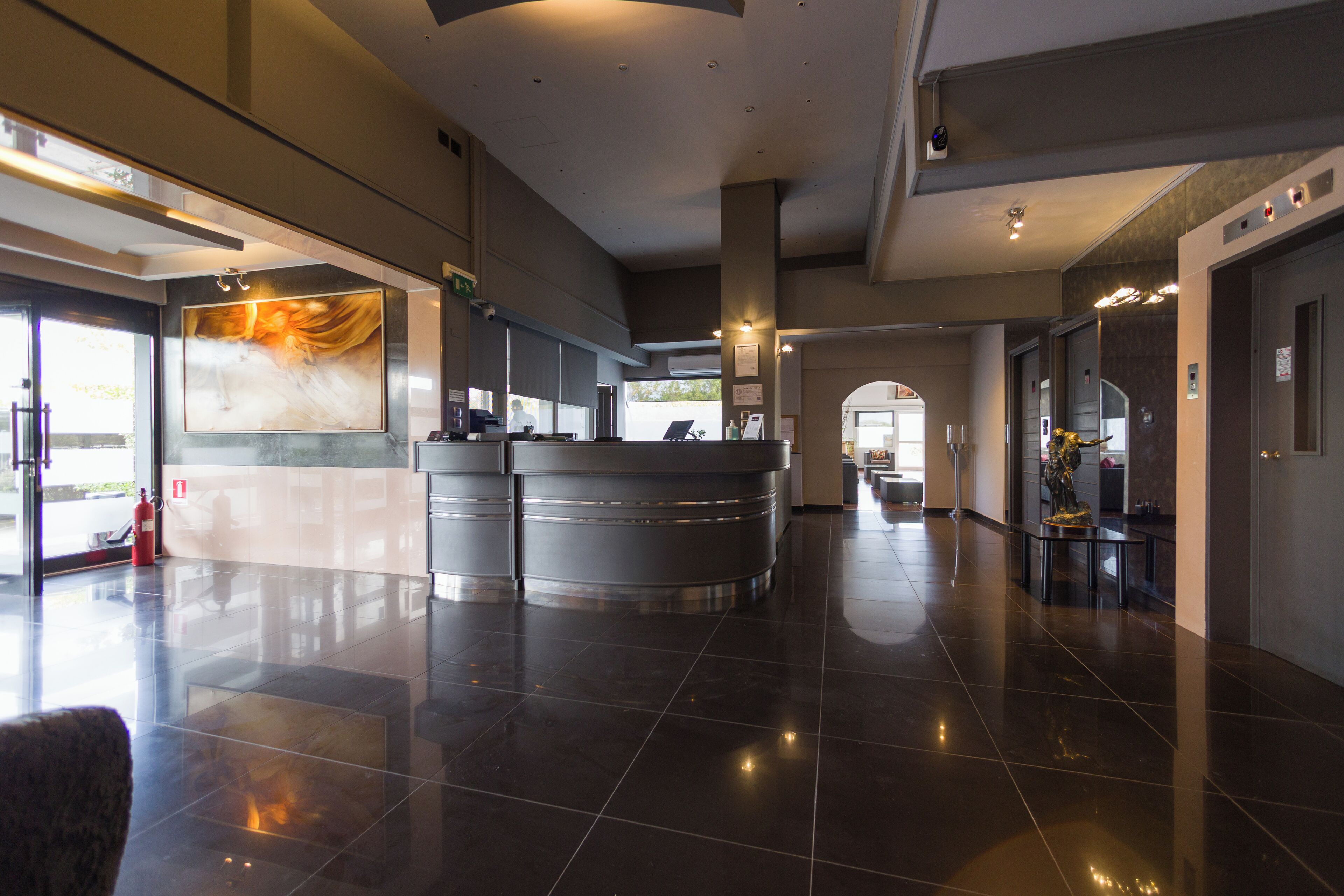 Um lobby moderno com uma mesa de recepção, um extintor de incêndio e uma janela grande.