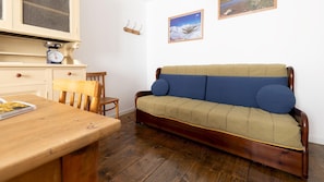 Um quarto aconchegante com uma mesa de jantar de madeira, um sofá de madeira com almofadas azuis e uma cadeira de madeira.