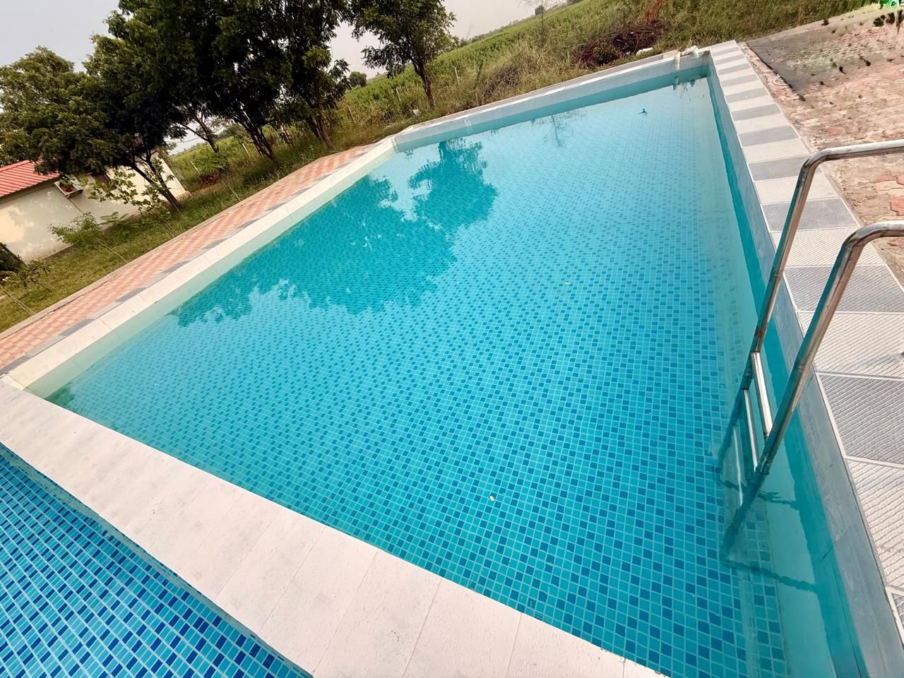 Piscina retangular com borda revestida e escada de metal.