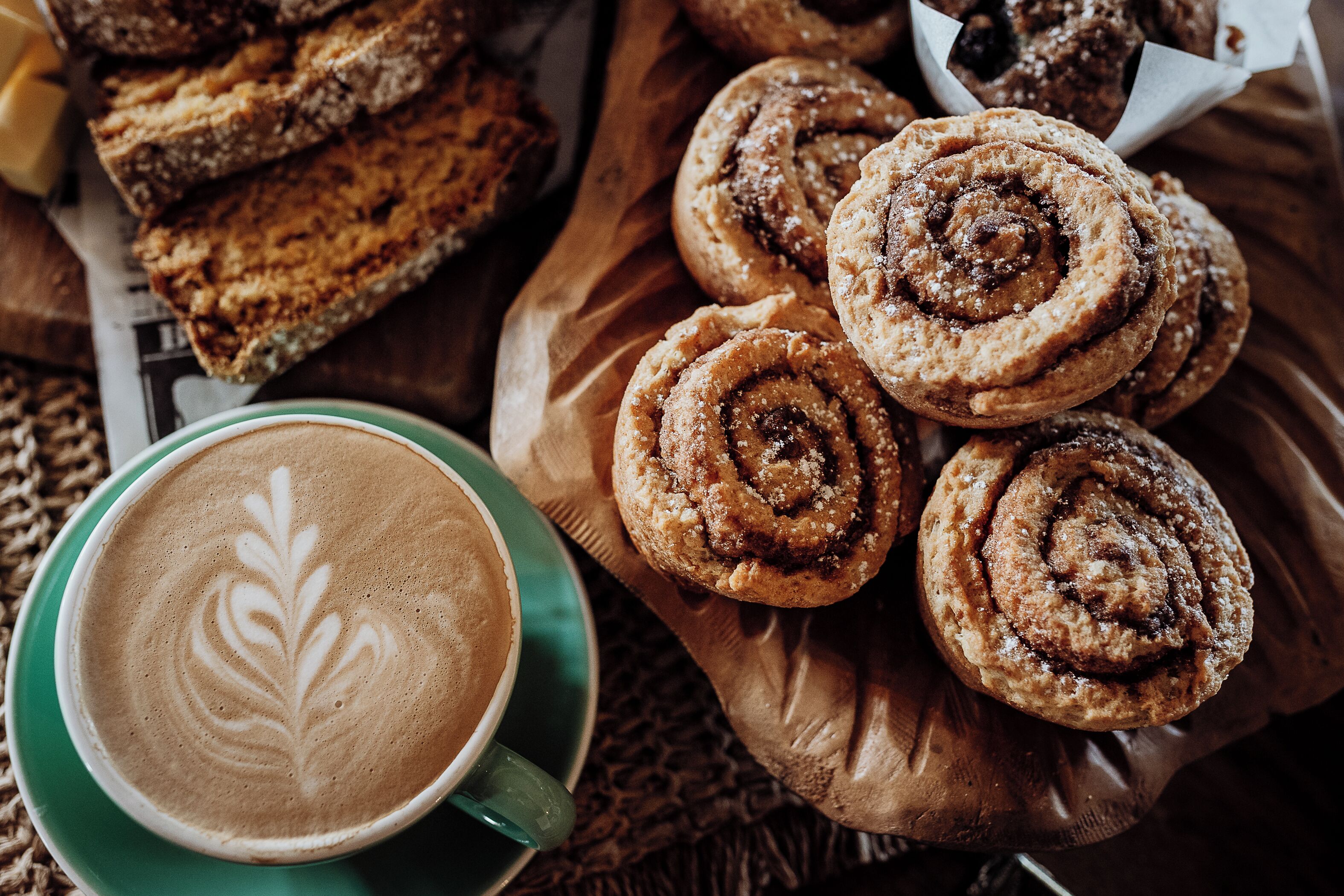 Uma chávena de café com arte de latte e um prato de canecas de canela.
