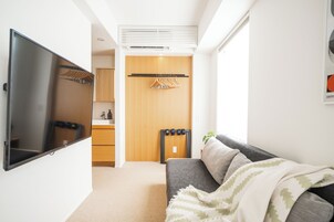 Uma sala de estar moderna com uma TV de tela plana, um sofá, uma parede de madeira e um porta-roupas.