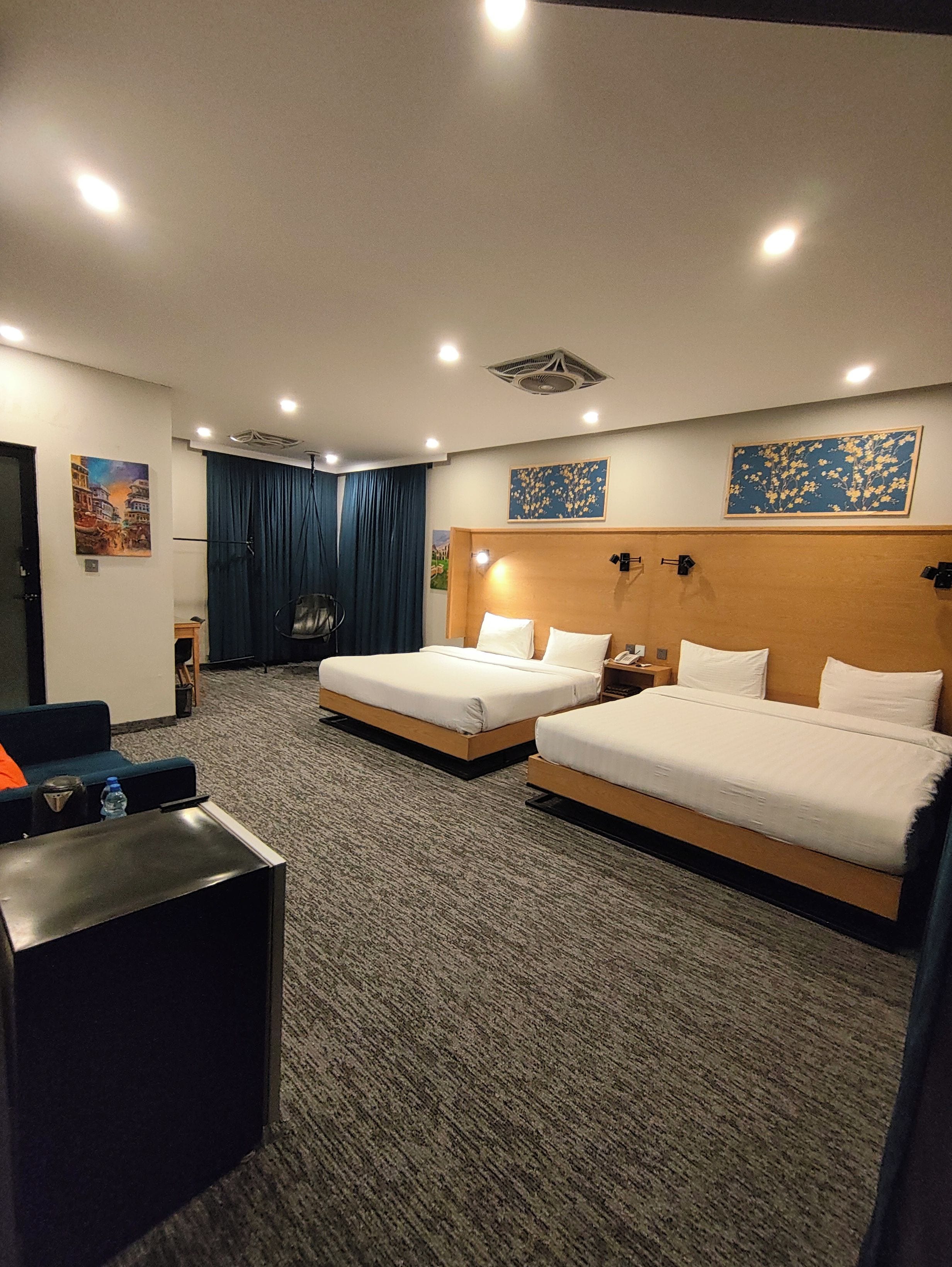Quarto de hotel com duas camas, uma escrivaninha e uma cadeira.