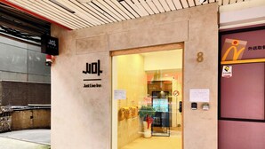 A entrada de um hotel com porta de vidro, uma placa com a inscrição "Just Live Inn" e o logotipo do McDonald's à direita.