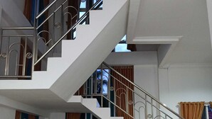 Um interior com vários níveis, incluindo escada, área de jantar e janelas com cortinas.