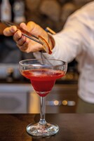 Um bartender preparando um coquetel com enfeite.