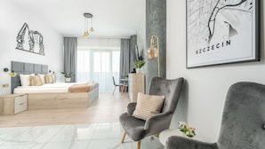 Quarto moderno com cama, poltrona cinza, mapa e escrivaninha com cadeira.