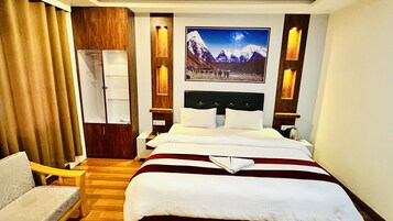 Quarto de hotel com uma cama grande, um guarda-roupa de madeira, uma escrivaninha e uma cadeira.