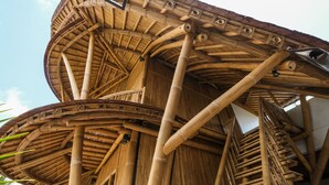Estrutura tradicional de bambu com vários telhados curvos e vigas de suporte.