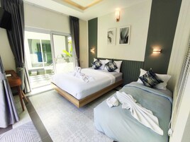 Quarto de hotel com uma cama grande, uma cama menor, uma escrivaninha e vista para o exterior.