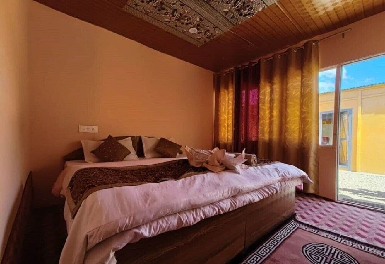 Quarto com cama, almofadas, manta e tapete estampado.