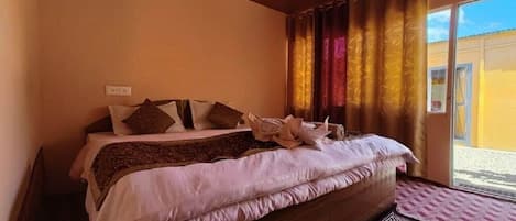 Quarto com cama, almofadas, manta e tapete estampado.
