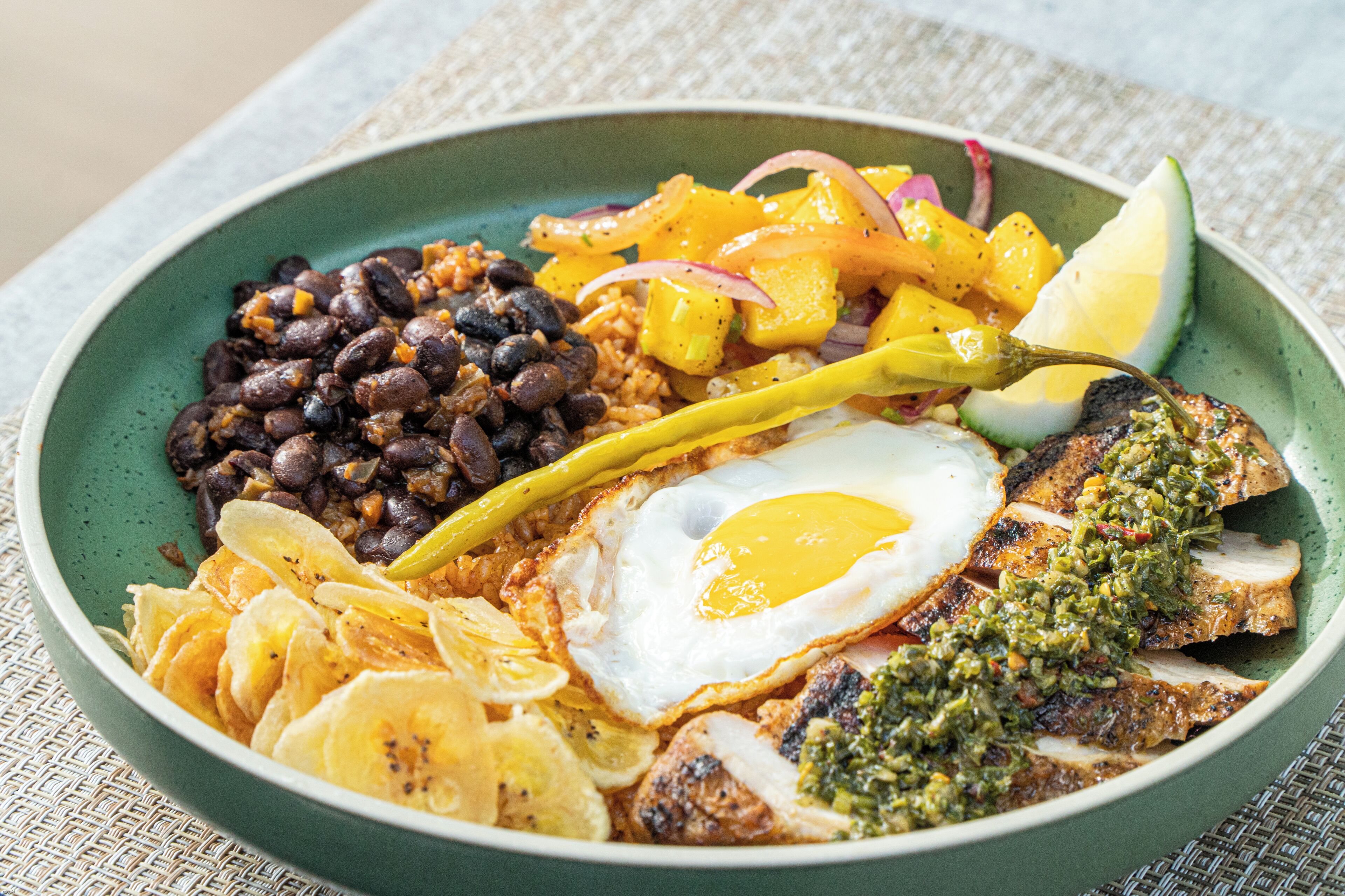 Prato com feijão, arroz, ovo frito, peixe e legumes.