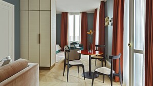 Quarto de hotel com cama, guarda-roupa, mesa de jantar com cadeiras e janela com cortinas.