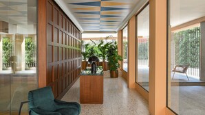 Interior moderno com um corredor comprido, painéis de madeira, uma área de estar com mesa e janelas amplas com vista para o verde.