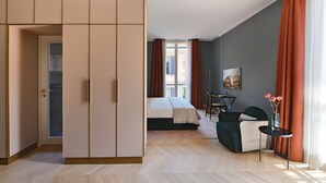 Quarto moderno com cama, área de estar e guarda-roupa.