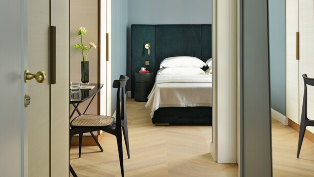 Quarto com cama, mesa de cabeceira e espelho.