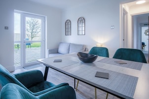 Uma sala de jantar moderna com uma mesa comprida, cadeiras azul-turquesa e um arranjo de tigelas no centro.