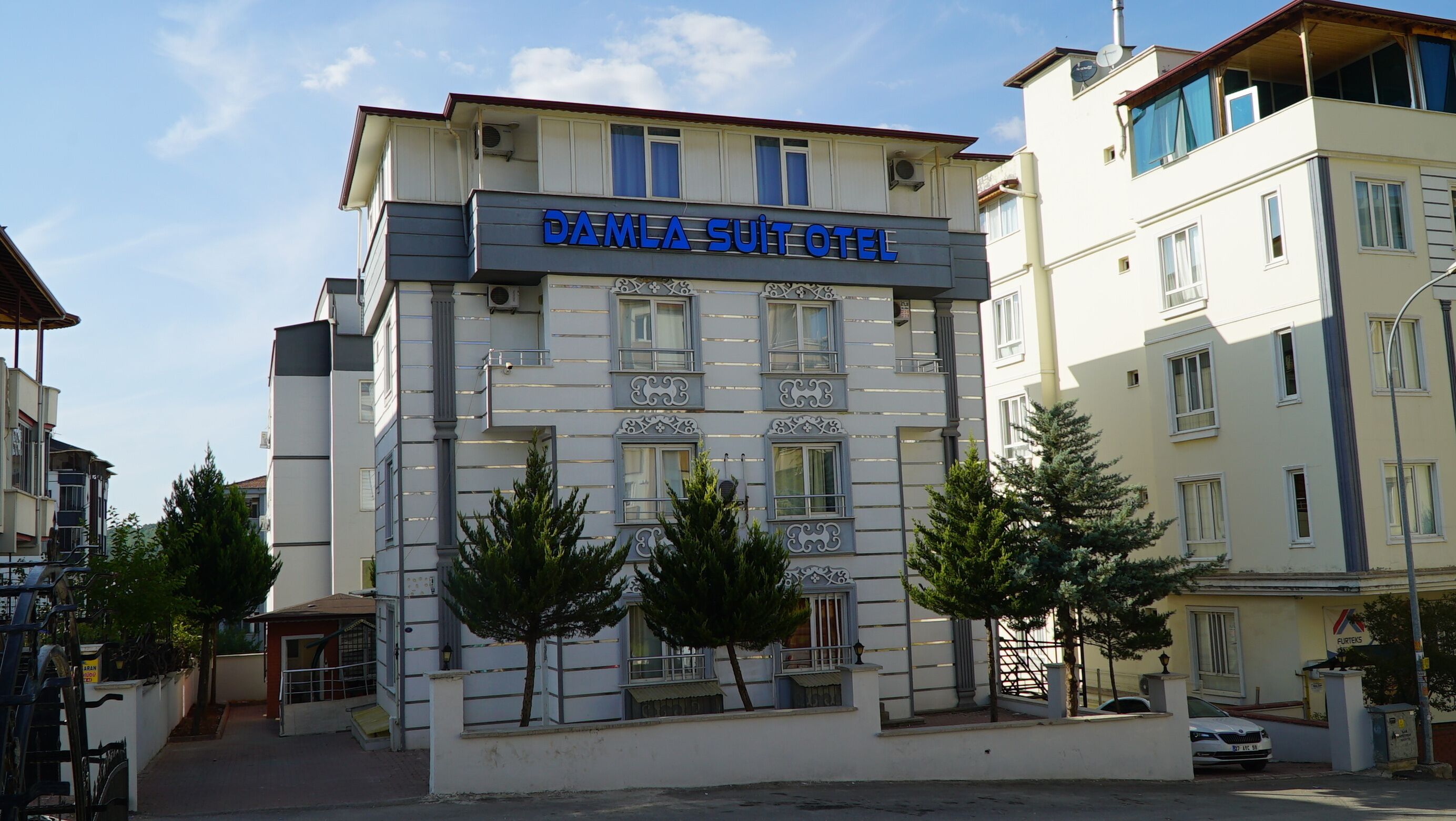 Um edifício com uma placa que diz “DAMLA SUIT OTEL”, indicando que se trata de um hotel.