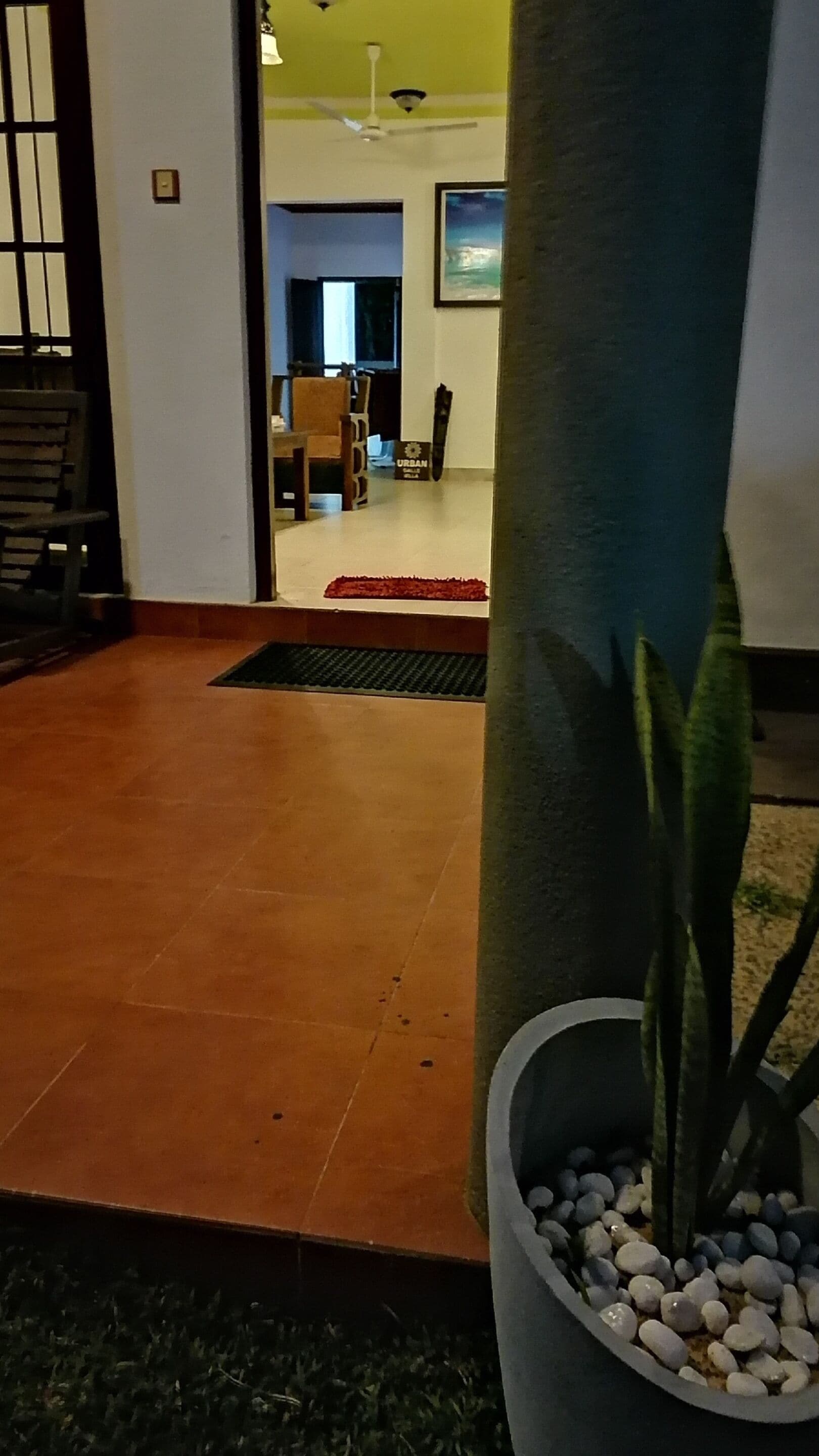 Um quarto com piso de azulejos, um pilar grande e uma planta em vaso.