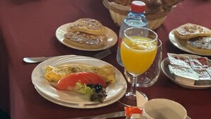 Mesa de café da manhã com pratos de comida, croissants e suco de laranja.