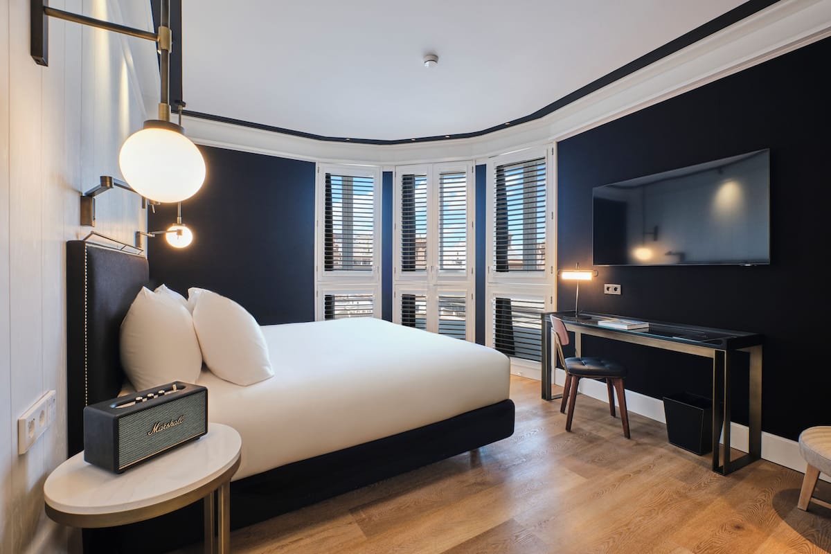 Quarto moderno com cama grande, escrivaninha e televisão.