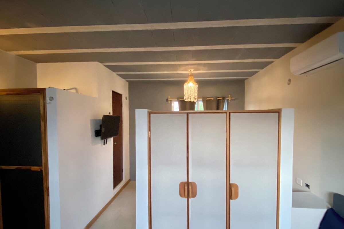 Quarto com guarda-roupa espaçoso, ventoinha de teto e luminária pendente.