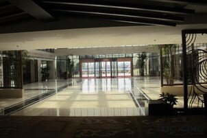 Um lobby amplo com entrada de vidro, piso estampado e design moderno no teto.