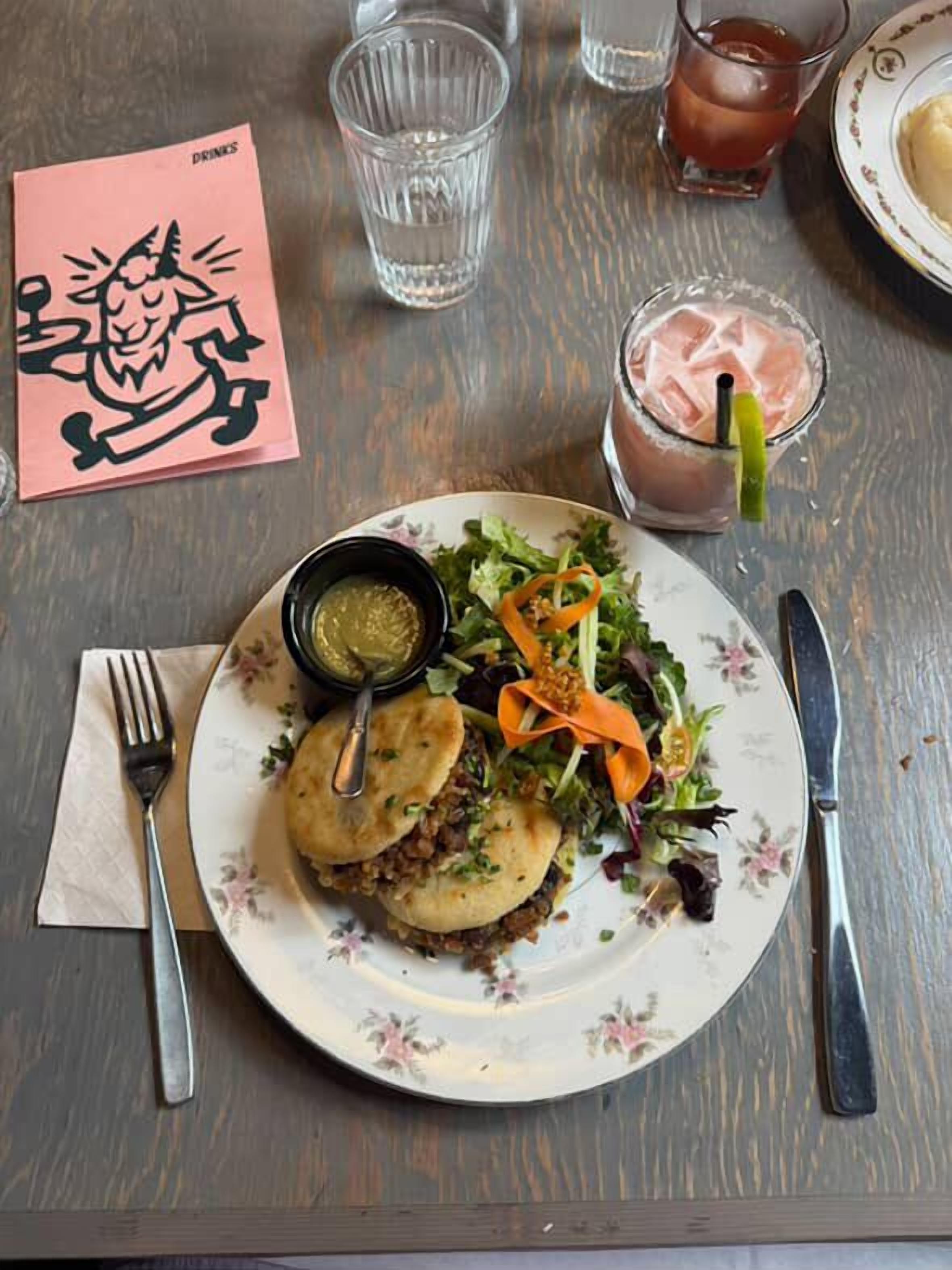 Prato de comida com salada, bebida e cardápio.