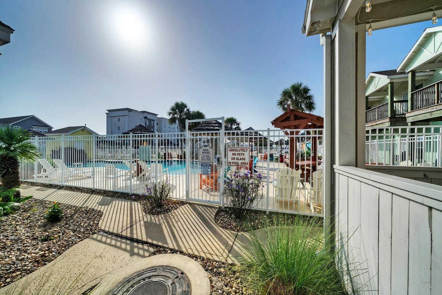 Área da piscina cercada, com espreguiçadeiras e aviso proibindo animais e vidro na piscina.