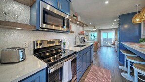 Cozinha moderna com forno embutido, micro-ondas e torradeira, uma janela ampla e um espaço de refeições com banquetas.