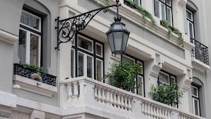 Um edifício de vários andares com varandas, janelas amplas e detalhes em ferro forjado.