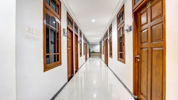 Um corredor longo e estreito com portas e janelas de madeira em ambos os lados, que leva a uma área de cozinha no final.