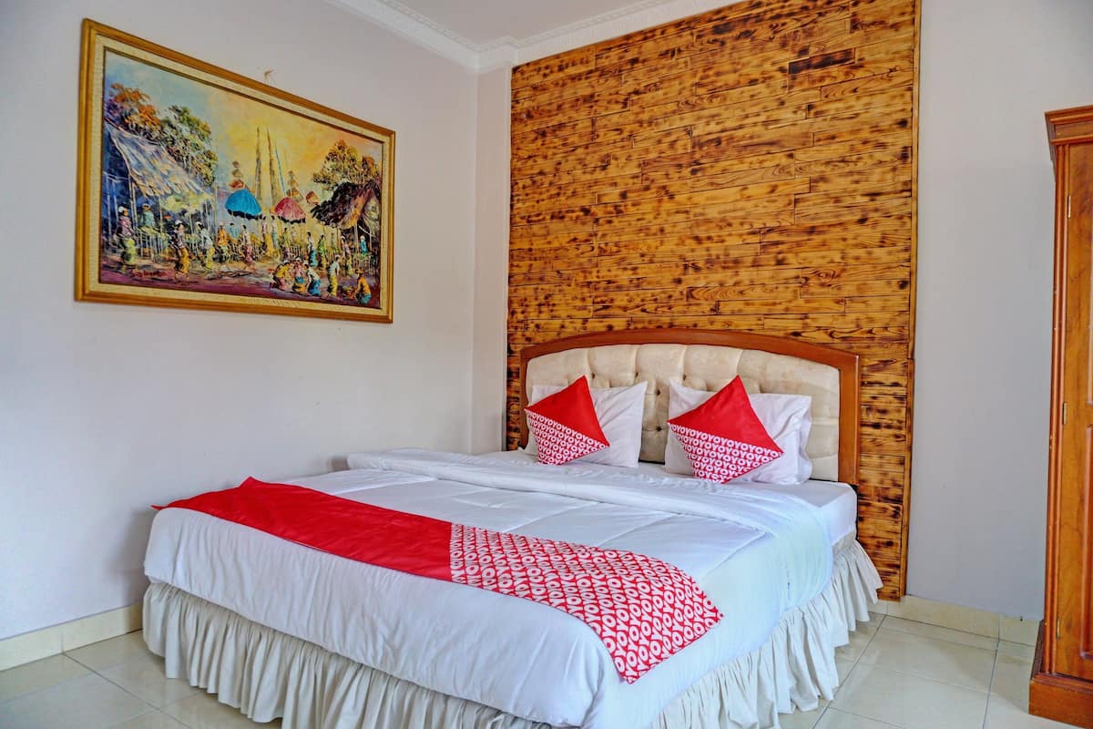 Quarto de hotel com cama, cabeceira de madeira, um quadro na parede e um guarda-roupa.