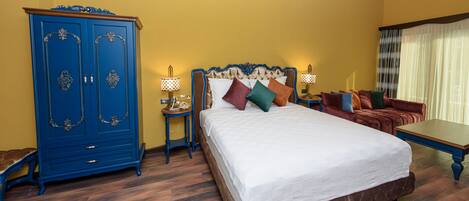 Quarto de hotel com uma cama grande, um guarda-roupa, um sofá e duas luminárias.