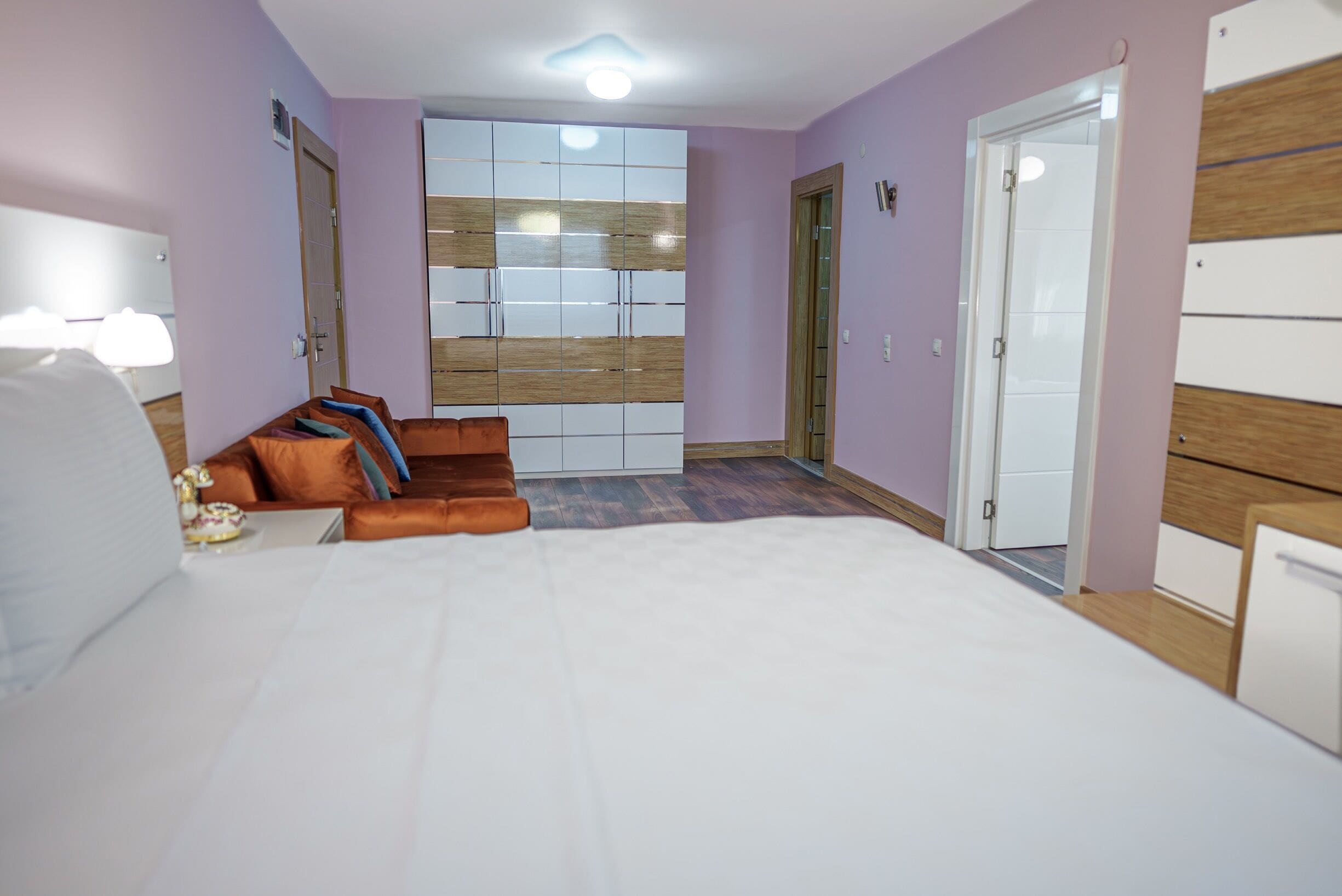 Quarto com cama, sofá, guarda-roupa e porta.