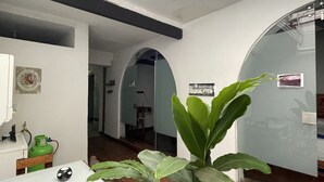 Uma área de recepção com balcão, um cilindro de gás verde, um vaso de planta e um espelho.
