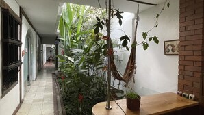 Um corredor com parede de tijolos, um banco de madeira e plantas penduradas.