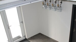 Quarto com soalho em mosaico, grades de metal preto, uma porta e janela com vista.