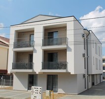 Um edifício moderno de vários andares com varandas, grandes janelas e aparelhos de ar condicionado externos.