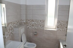 Casa de banho com sanita, lavatório e janela.