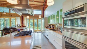 Cozinha moderna com eletrodomésticos de aço inoxidável, uma ilha grande e janelas amplas com vista para o exterior.