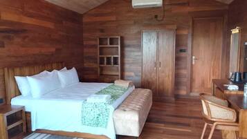 Um quarto tipo cabana de madeira com cama, um banco, mesa de cabeceira e uma pequena escrivaninha com cadeira.