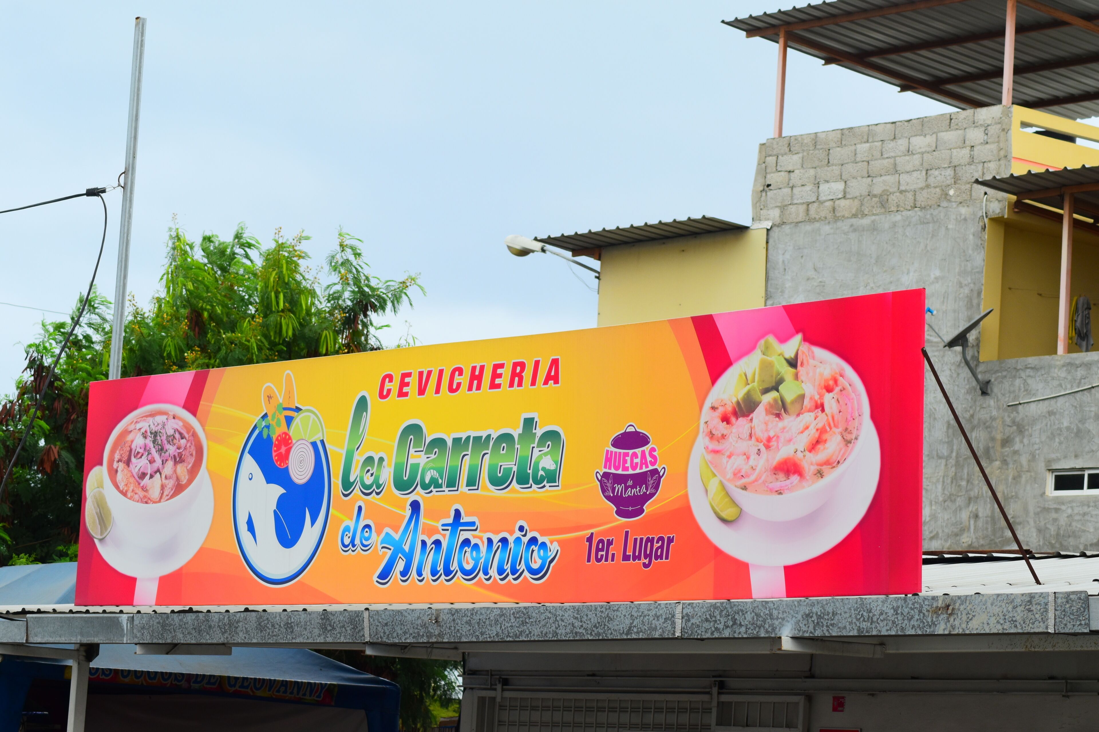 Um outdoor publicando 'Le Carreta de Antonio', com imagens de comida e um marcador de localização.