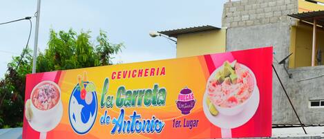Um outdoor publicando 'Le Carreta de Antonio', com imagens de comida e um marcador de localização.