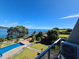 Piscina com vista para o mar, cercada por vegetação e área delimitada por uma cerca.