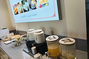 Balcão de café da manhã com máquinas de café, chaleira e dispensador de suco.